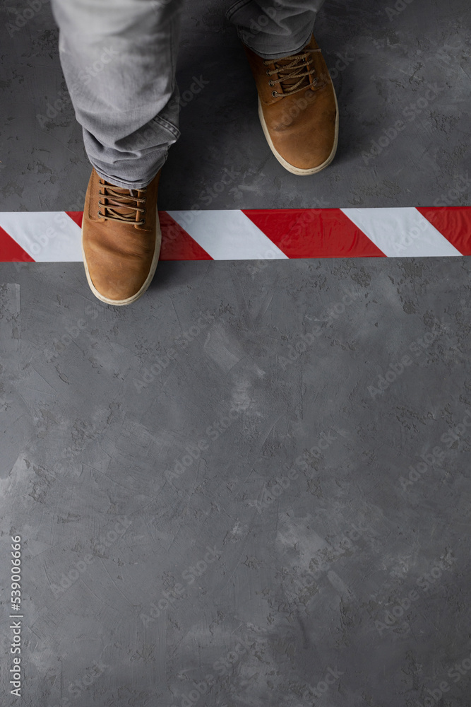 Man stepping over signal warning tape at cement floor background ...