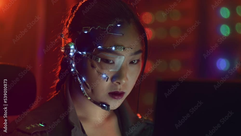 A Cyberpunk girl works on the computer in the red neon lights. Asian ...