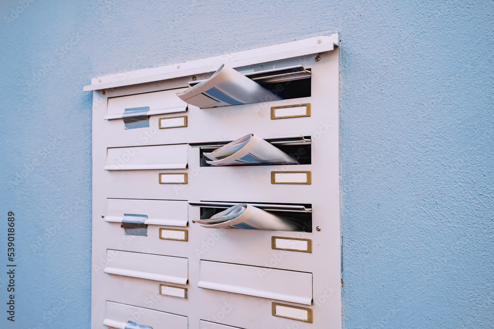 The mailbox of a residential building with daily newspapers sticking ...