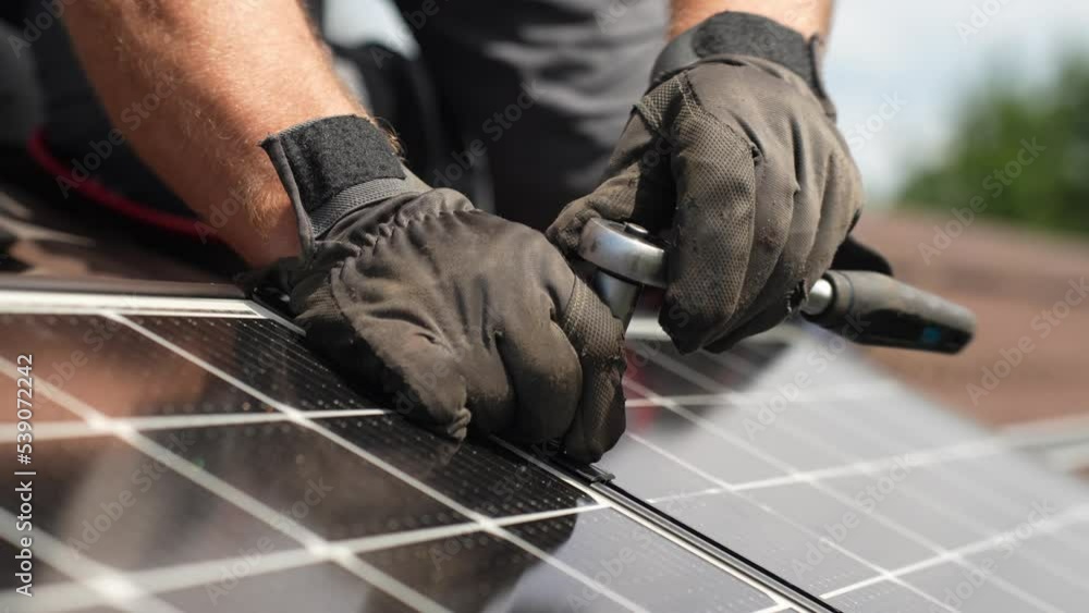 Technician bolting solar panels together on roof for sustainable future ...