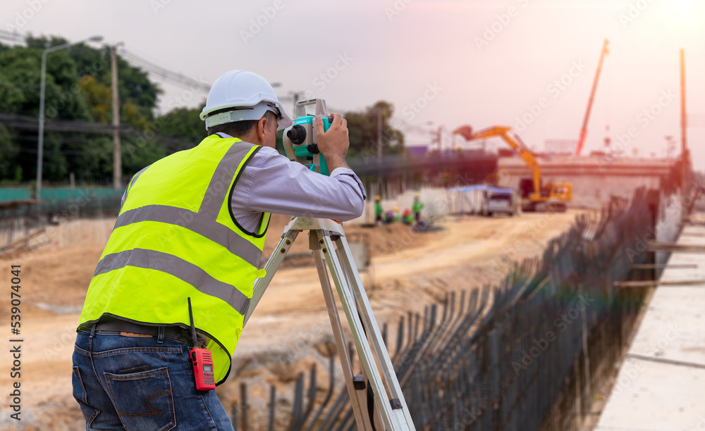 Surveyor engineer wearing safety uniform and helmet with equipment ...