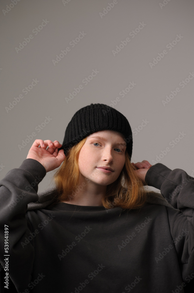 young girl model in black cap and grey jackett isolated on grey ...