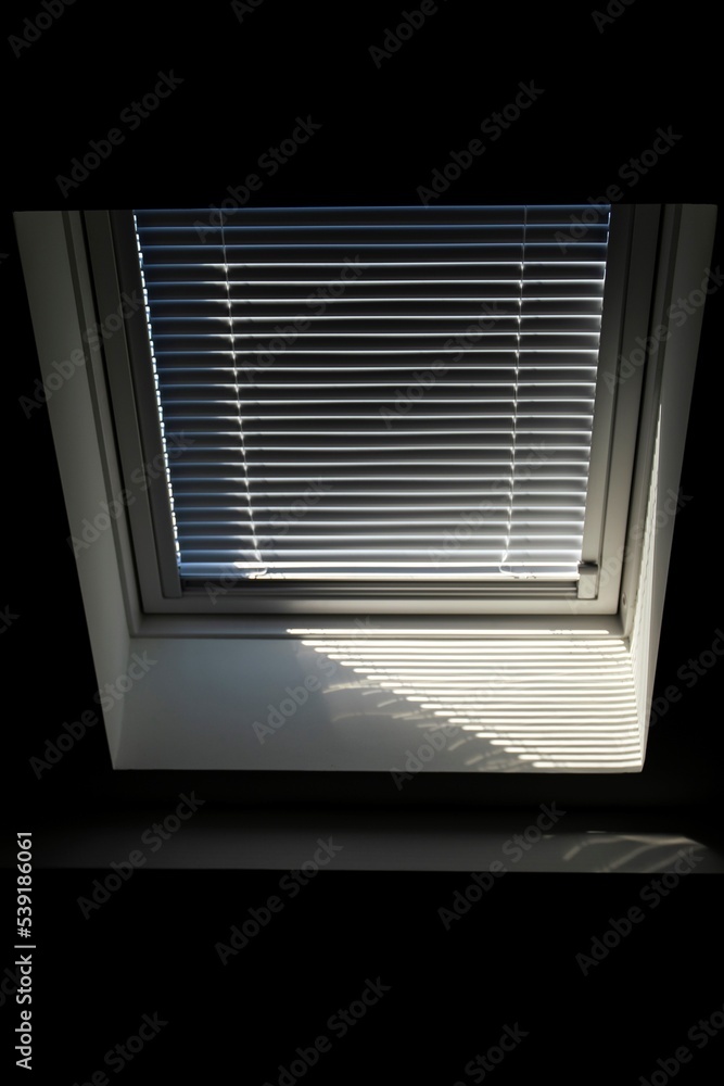 A portrait of a velux roof window with a half open jalousie in it to ...