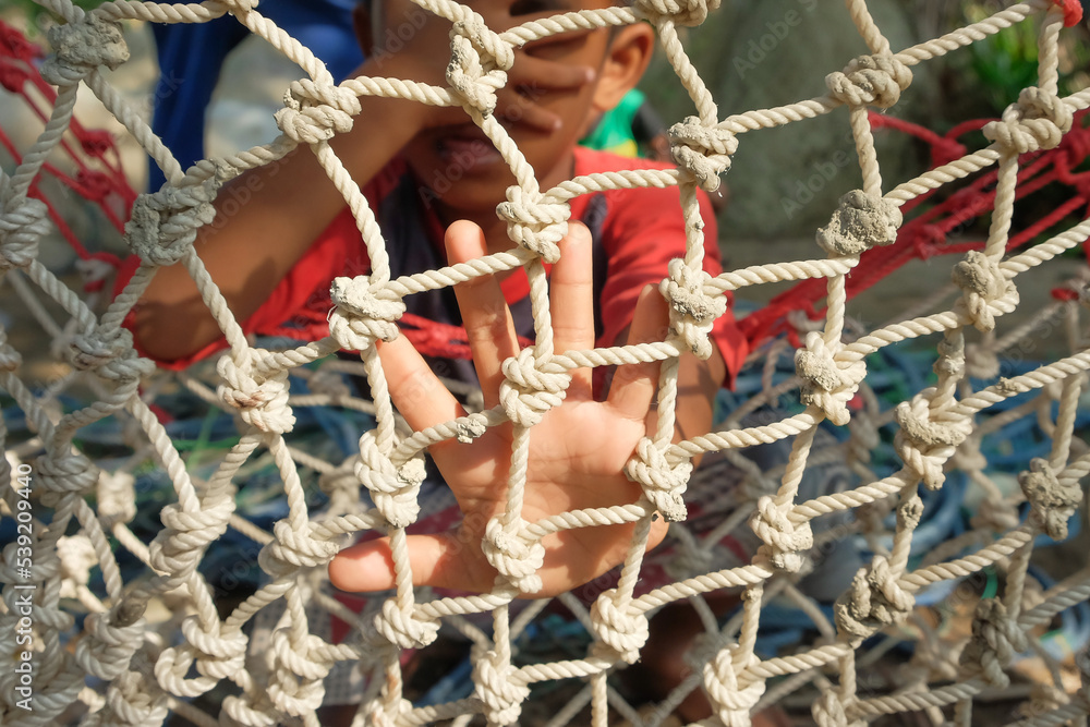 Little boy showing hand signal in rope net to stop. Stop abusing, fear ...