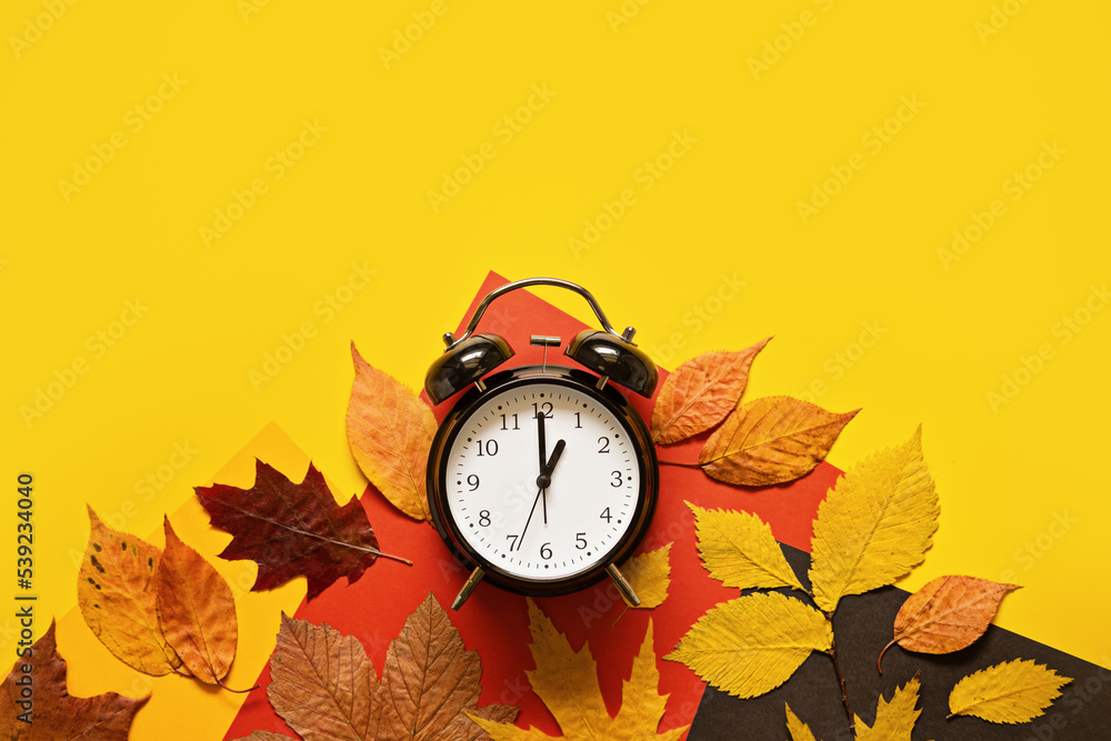 Daylight saving day. Fall Back. Black Alarm clock and autumn leaves on ...