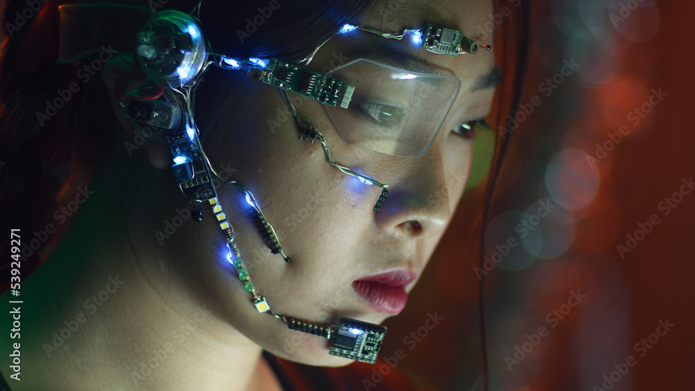 Focused asian girl in cyberpunk attire works on the computer. Wearing ...