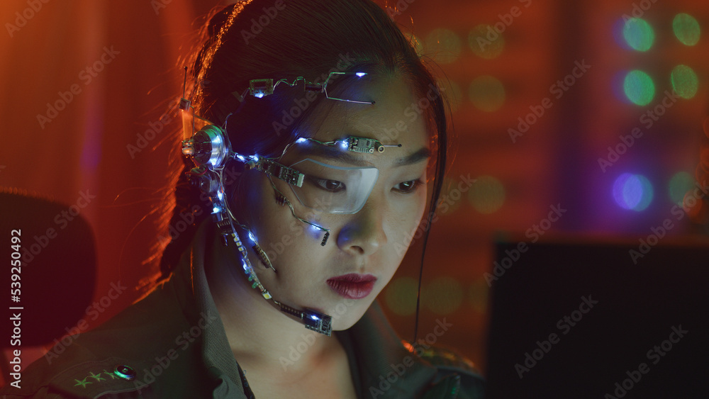Focused asian girl in cyberpunk attire works on the computer. Wearing ...