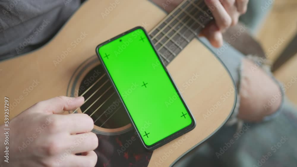 Vidéo Stock Man playing acoustic guitar. Tutorial with laptop computer ...