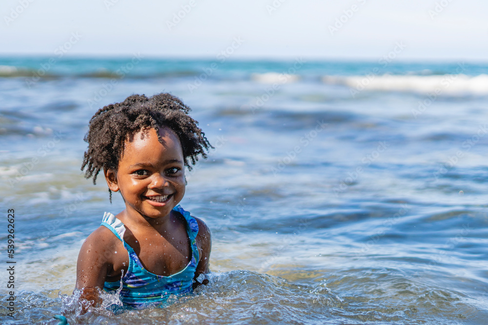 Retrato horizontal de una hermosa niña afroamericana con cabello afro muy sonriente disfrutando ...