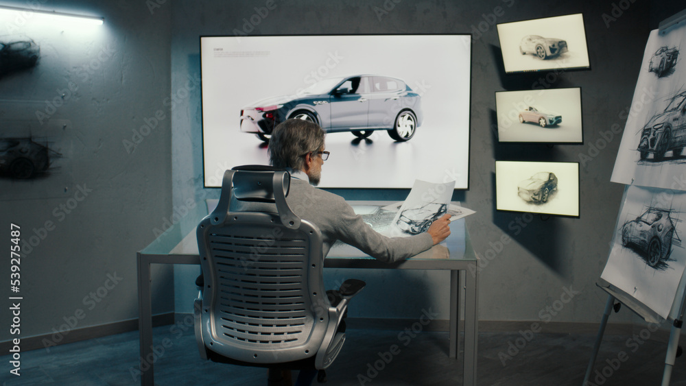 Back view of an automotive graphic designer draws sketch of the ...