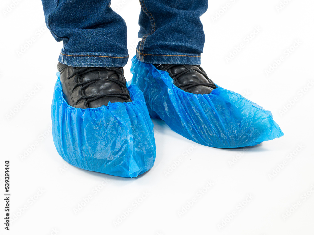 Blue medical shoe covers are worn over shoes on white background ...