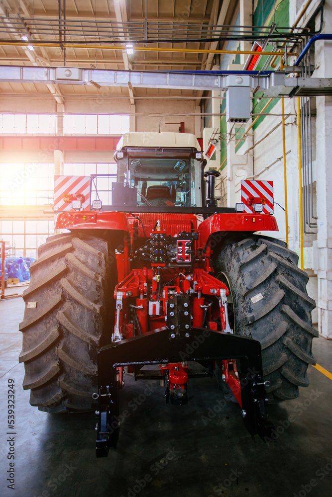 Rear view of modern agricultural tractor in hangar. Hydraulic hitch ...
