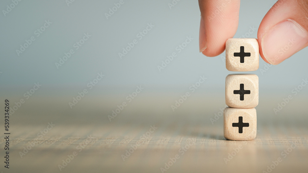 Plus sign in wooden cube block stacking. Addition and positive mindset ...
