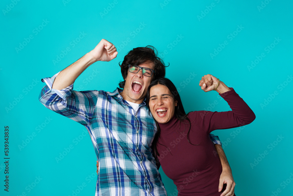 Excited young couple in love cheering for their victory, winning a ...