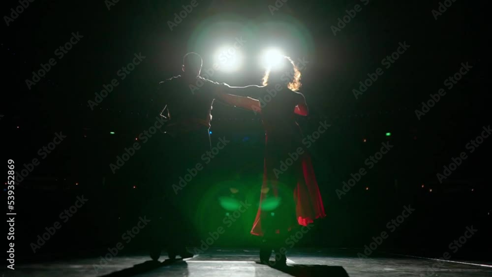 Ballroom dancers slowly coming out on stage in 2 bright spotlights.Rear ...
