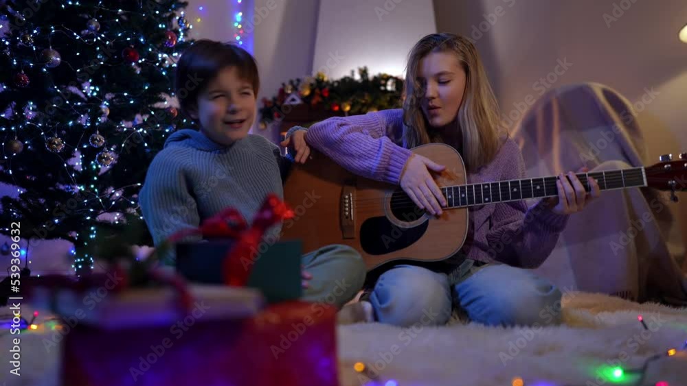 Talented teen girl playing guitar as cheerful boy singing dancing ...