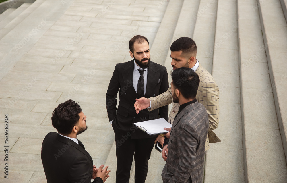 Business people outdoor meeting. A group of men in suits stands against ...