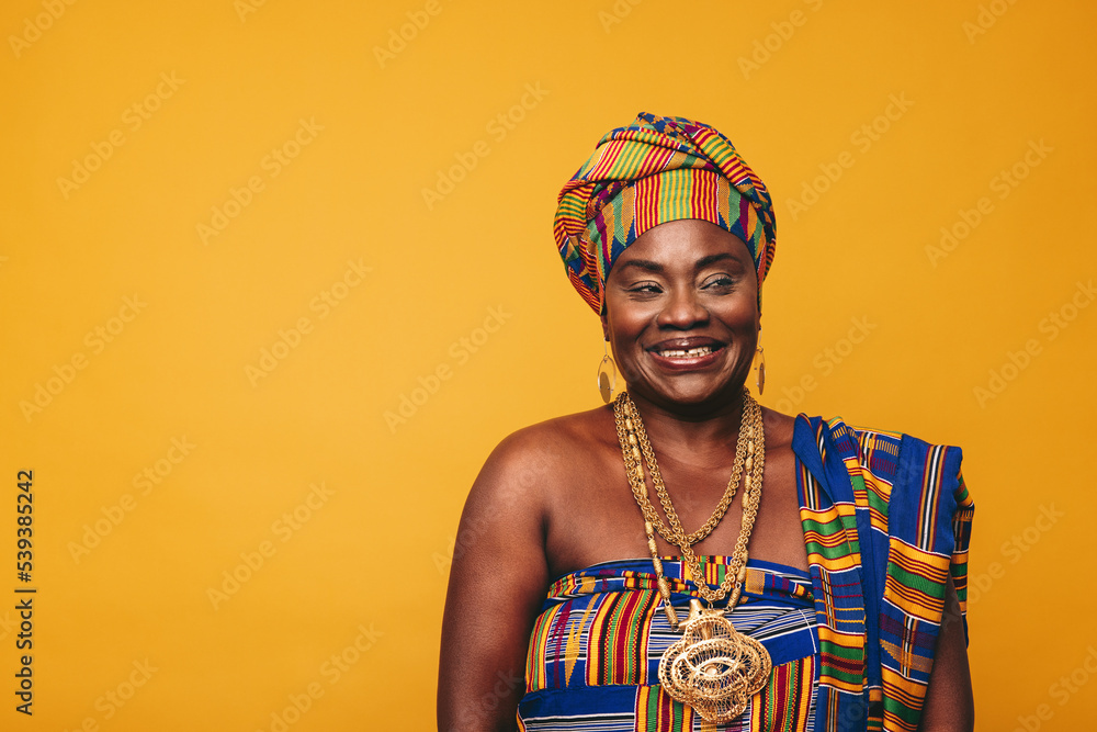 Smiling Ghanaian woman wearing elegant traditional clothing in a studio ...