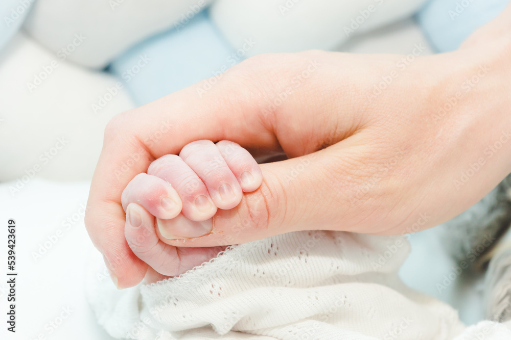 Newborn baby touching his mother hand. Mother uses her hand to hold her ...