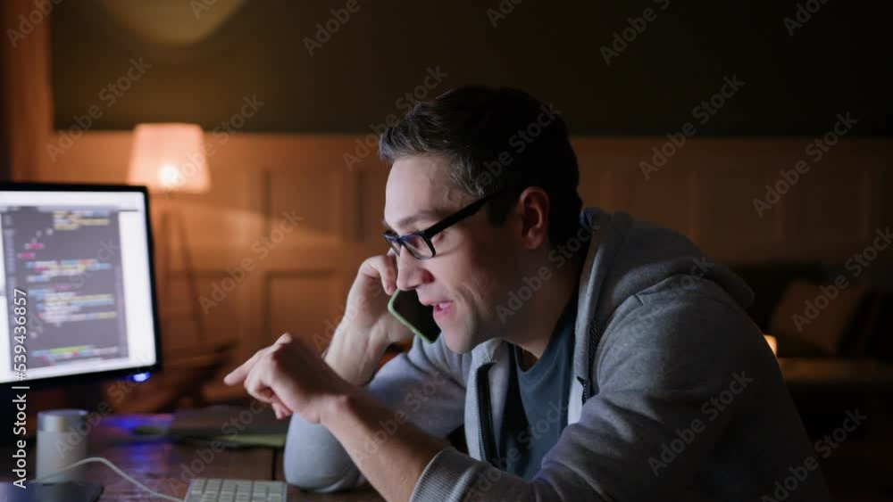 young man remote works in home office in the night, sitting at table ...