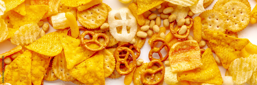 Salty snacks on a white table panorama. Party food banner. Potato and ...