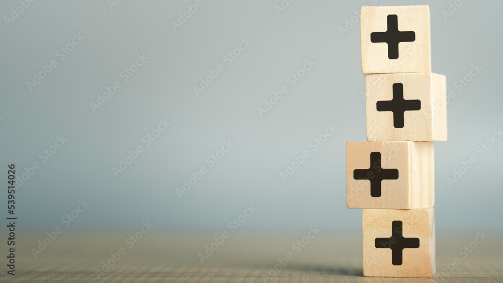 Plus sign in wooden cube block stacking. Addition and positive mindset ...