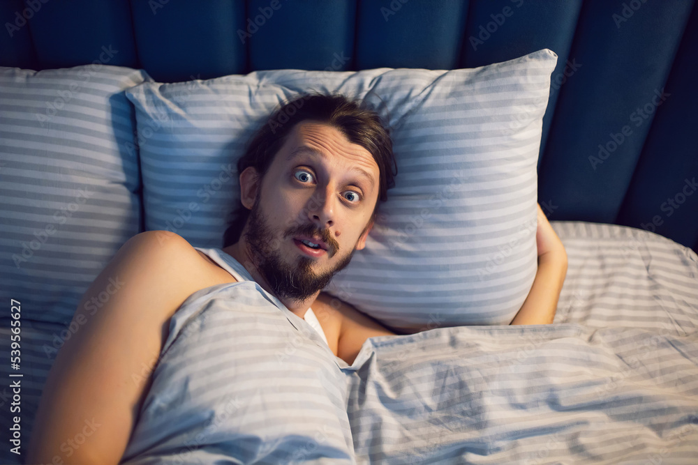 portrait of a man with a beard lying on the bed in the bedroom ...