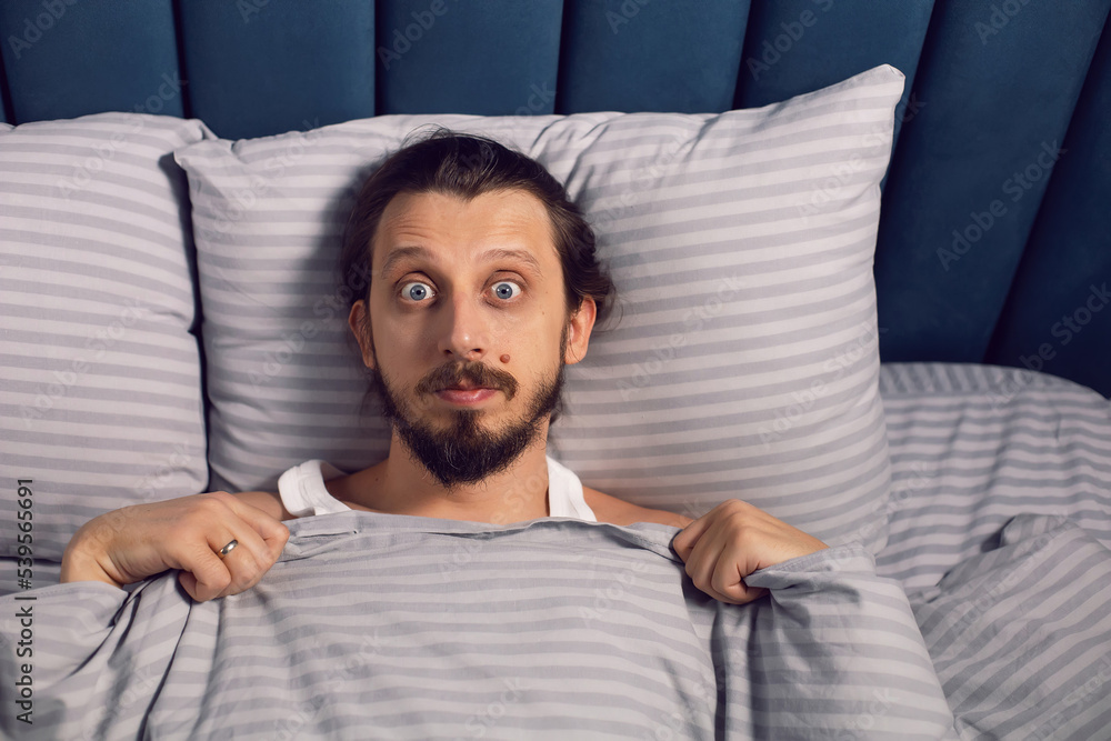 portrait of a man with a beard lying on the bed in the bedroom ...