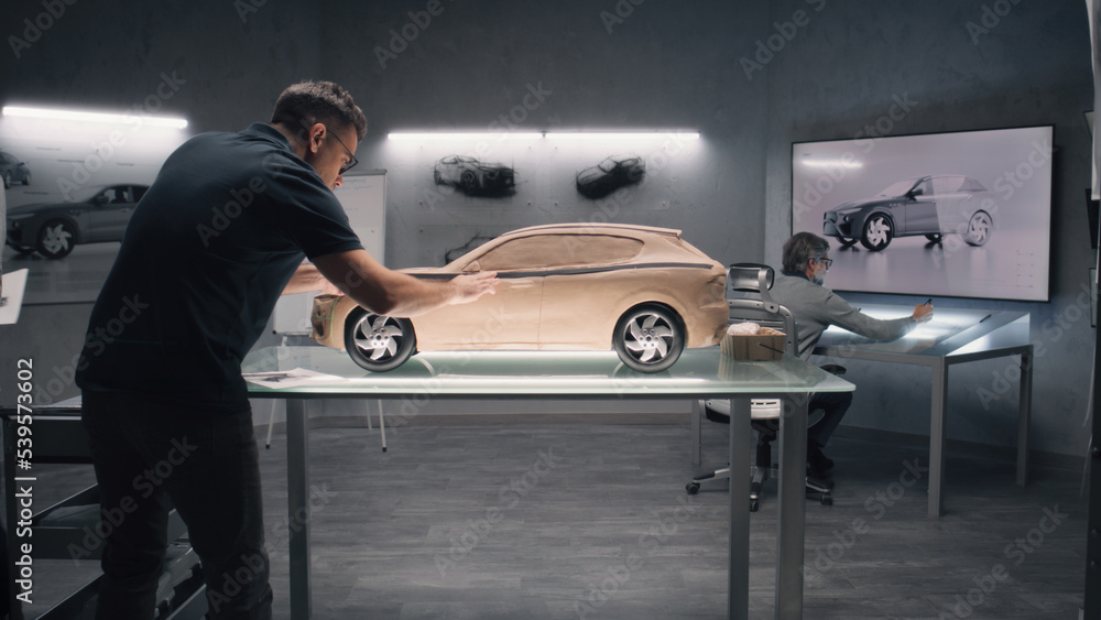 Two male automotive designers creating model of car in modern car ...