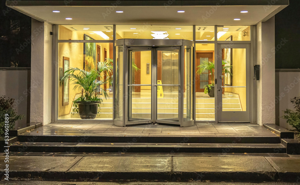 Apartment building lobby seen from street at night, , glass walls ...