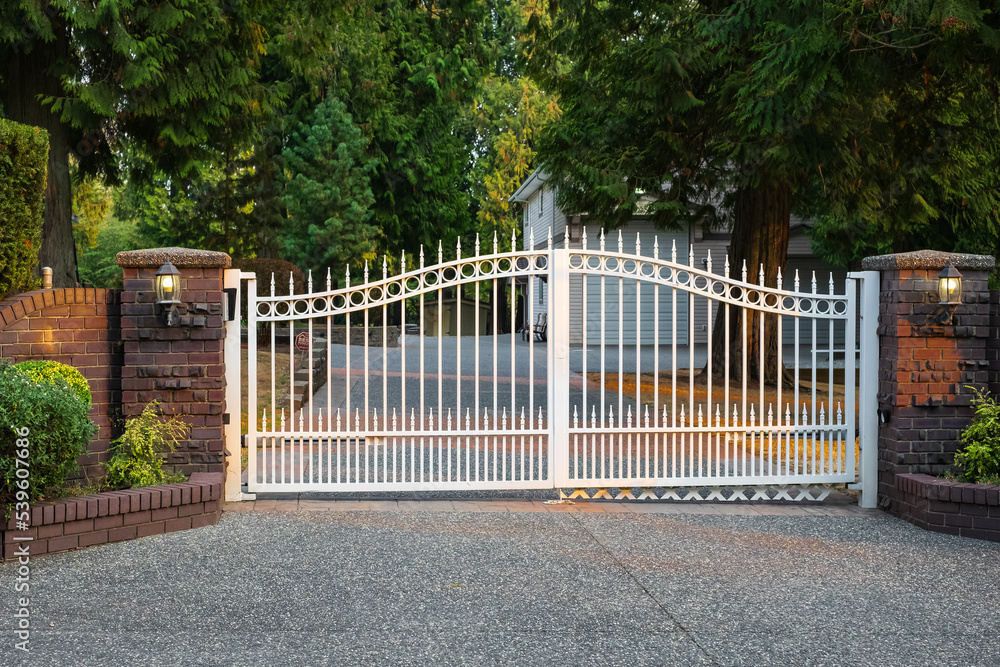 Iron front gate of a luxury home. Wrought iron white gate and brick ...
