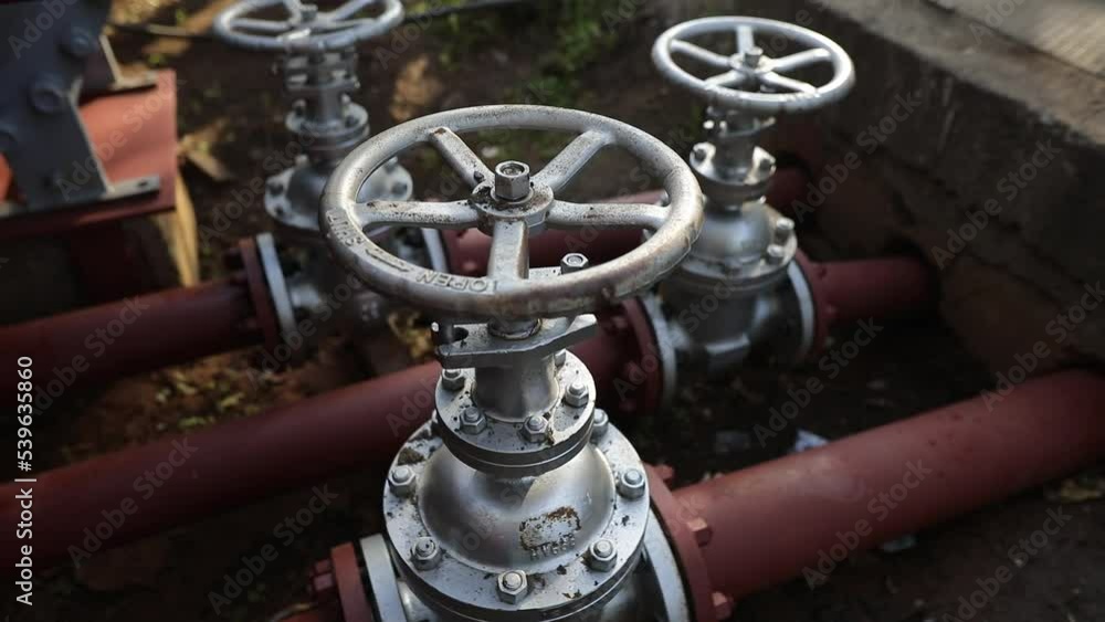 Handheld footage with industrial metallic pipe valves used to open or ...
