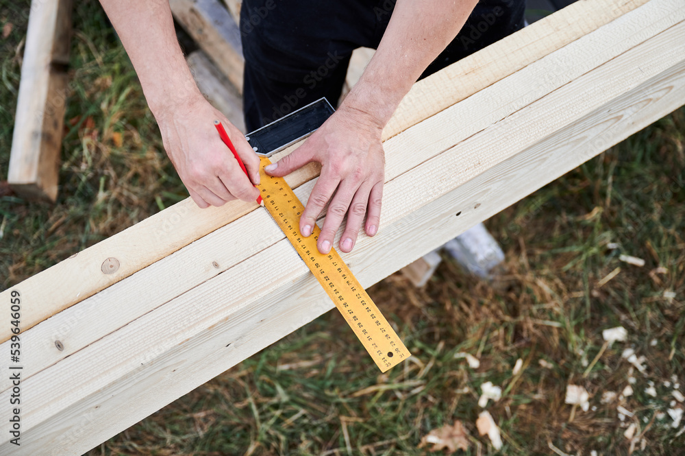 Man worker building wooden frame house on pile foundation. Close up ...