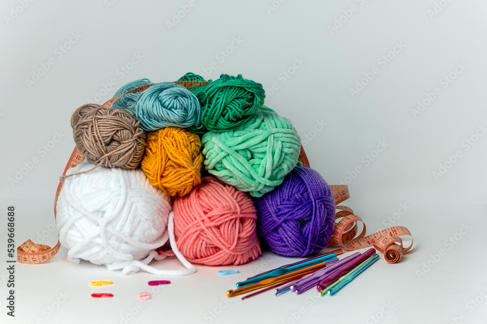 Multicolored crochet hooks of different diameters next to skeins of ...