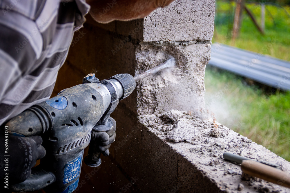 Ouvrier utilisant un perforateur pour percer un mur d'agglos Stock ...