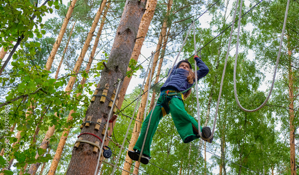 Child wins by climbing high rope, wearing mountain helmet and ...
