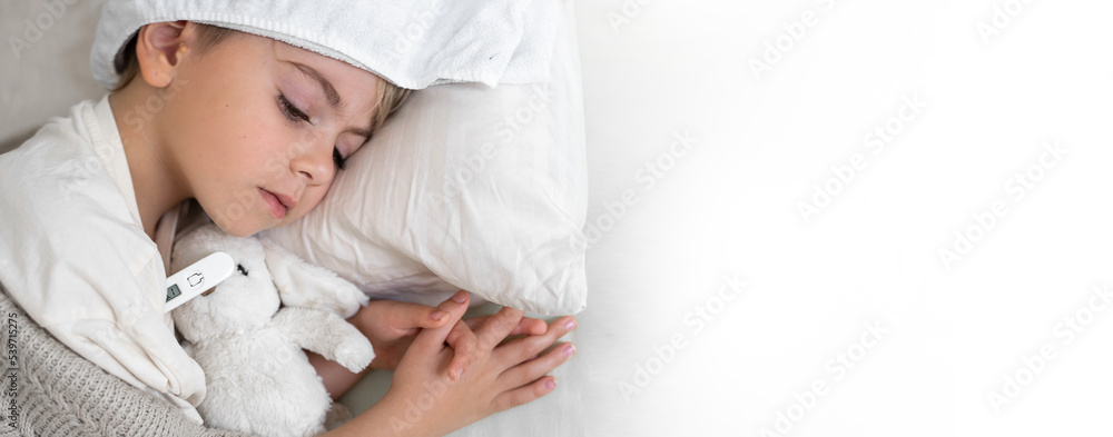 Sick fever child lying in bed with cold compress on his forehead ...