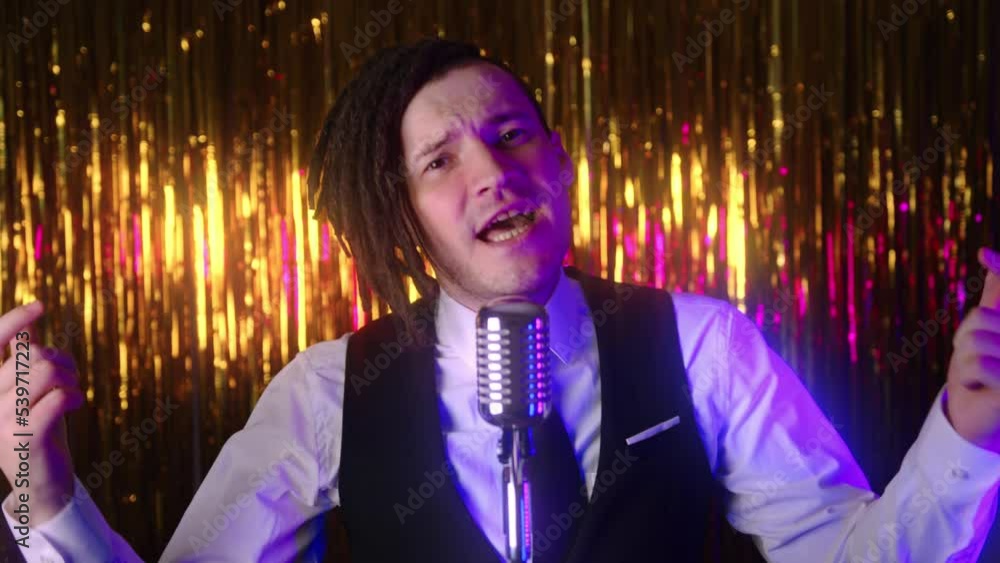 A white male hip-hop singer with dreadlocks in white shirt, black vest ...