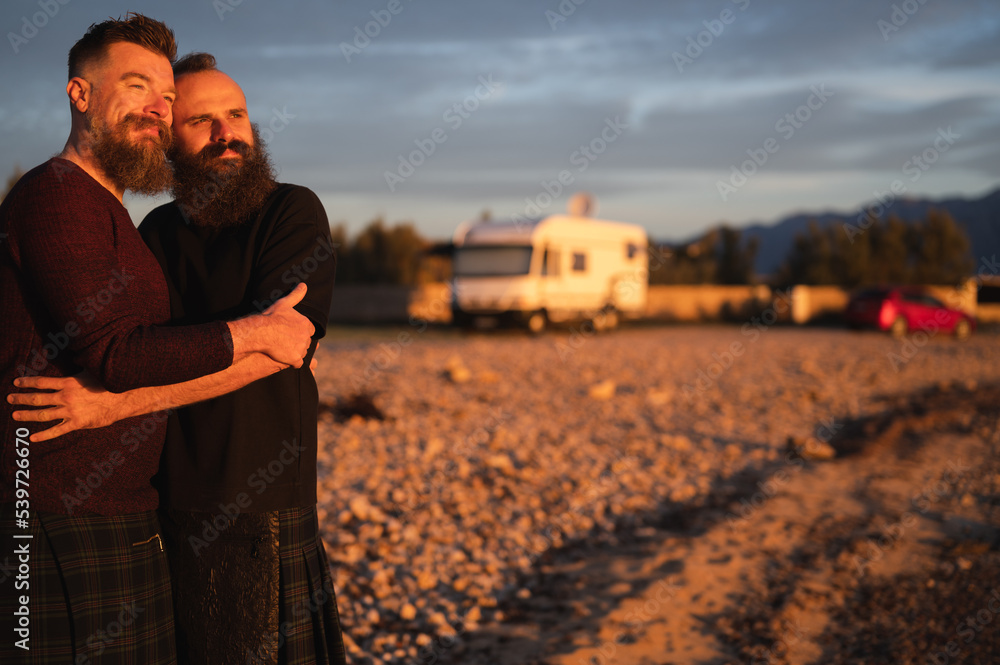 Attractive hipster gay couple enjoying sunrise on beach, sunbathing on ...