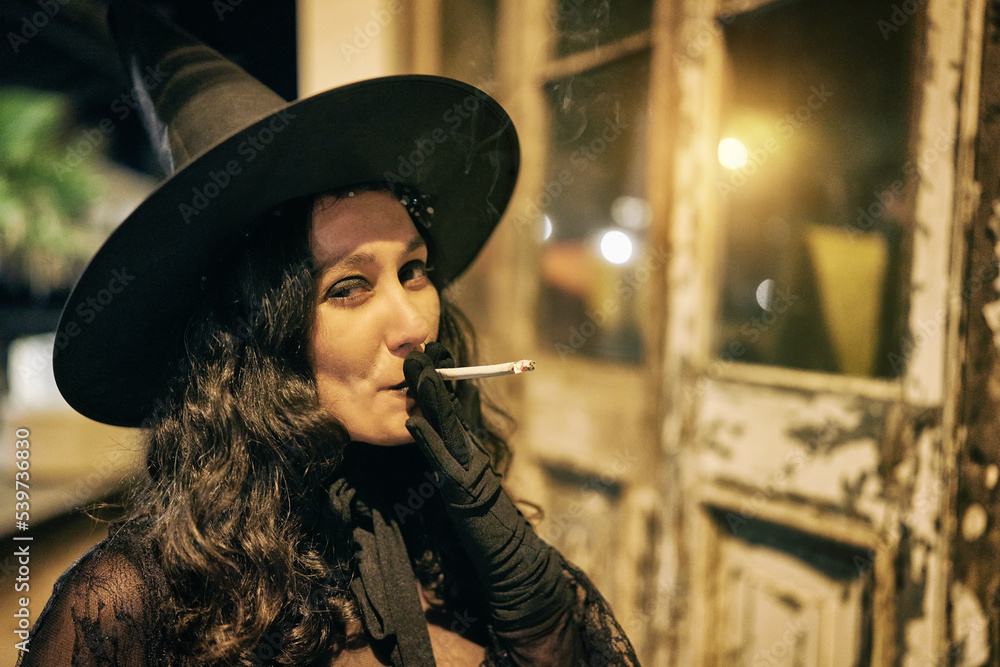 Latin Woman Dressed As A Witch Smoking A Cigar At Night Looking At The