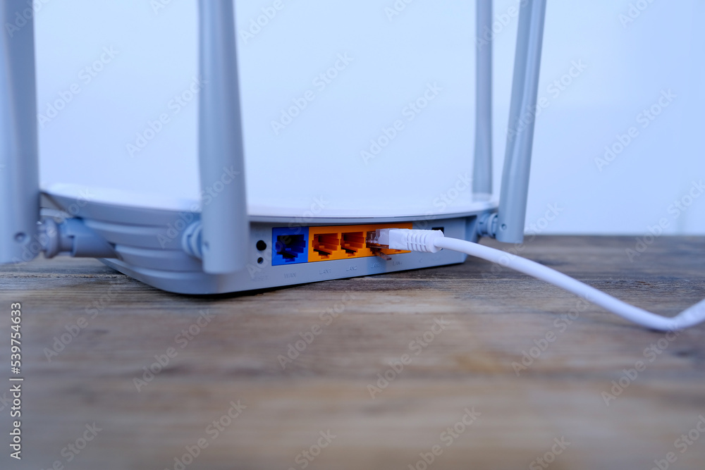 white cable is plugged into the port of Wi-Fi router, modern wireless ...