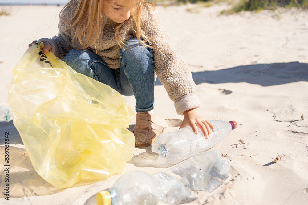 little girl with trash bag cleaning up the beach. Child collects ...