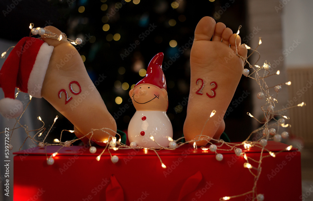 numbers 2023 are written on bare feet of child, small hat of Santa ...