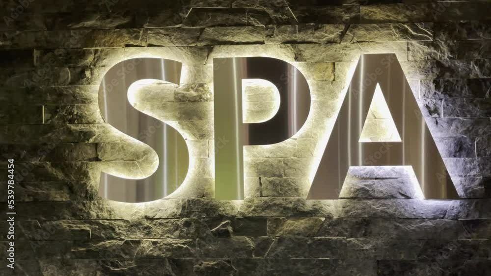 Advertising sign spa area on a black brick wall Stock Video | Adobe Stock