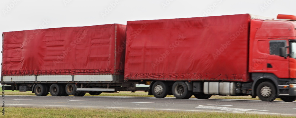 Heavy red awning truck with tented trailer drive on highway road . Side ...