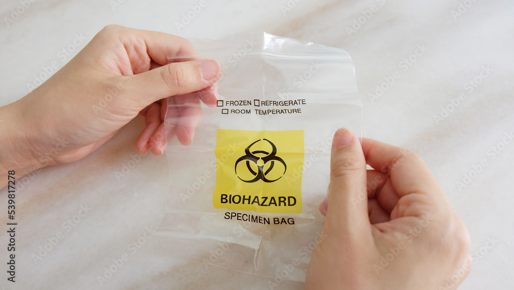 Hands holding a new and empty medical specimen waste bag with the ...