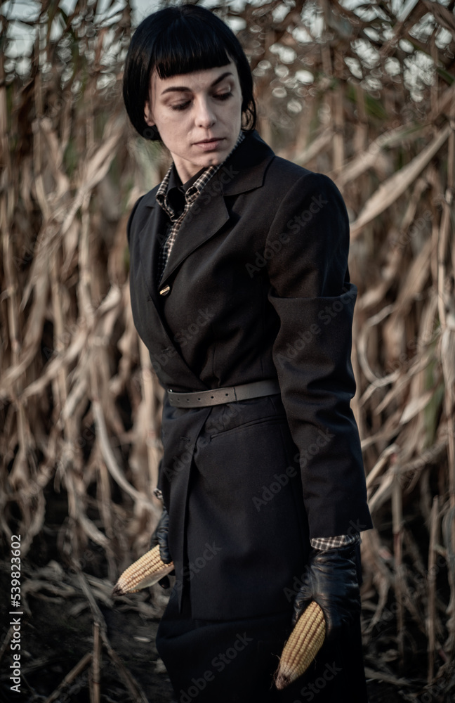On an autumn evening, a girl in a black business suit stands in a field ...