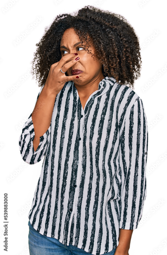 Young african american girl wearing casual clothes smelling something ...