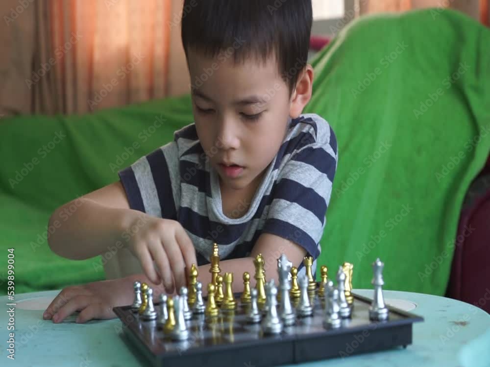 Cute little boy playing chess. Young boy intensely develops chess ...