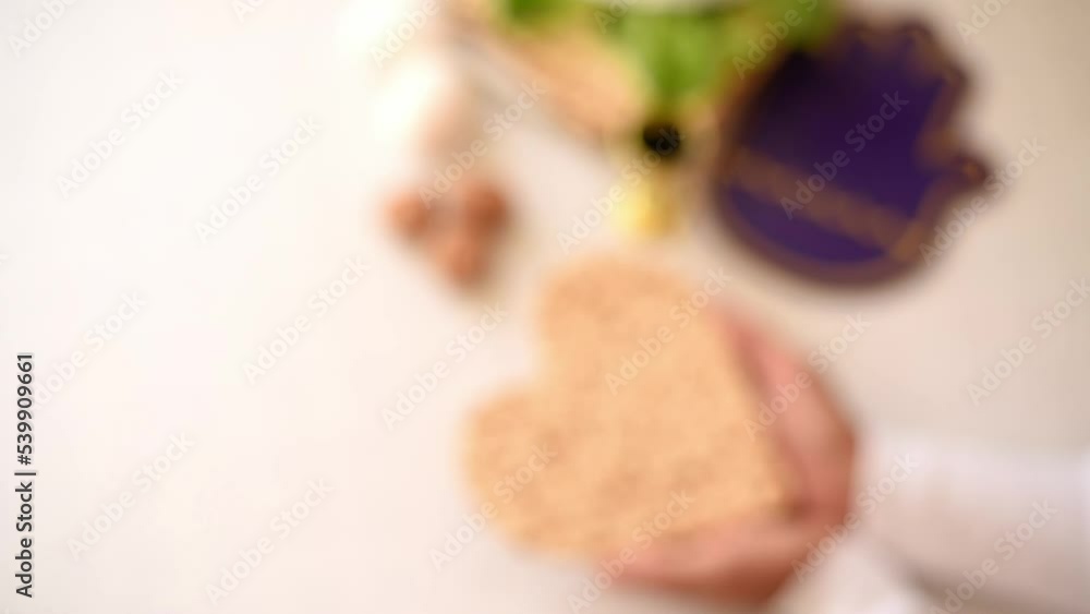 selective focus, blurred woman's hands holds Matzah shape of heart ...